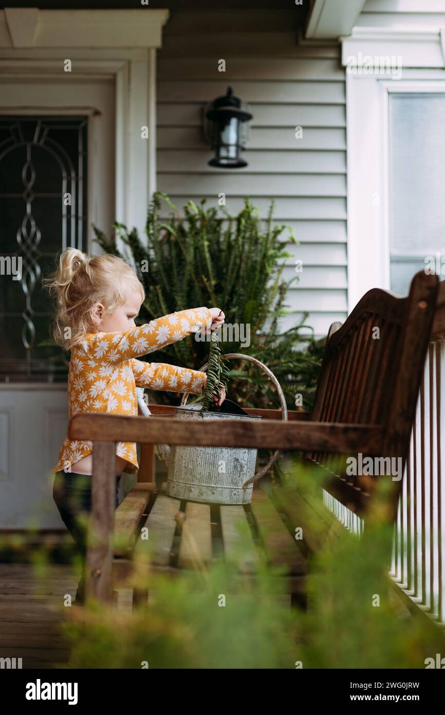 Young child helping with front porch plants at home Stock Photo - Alamy