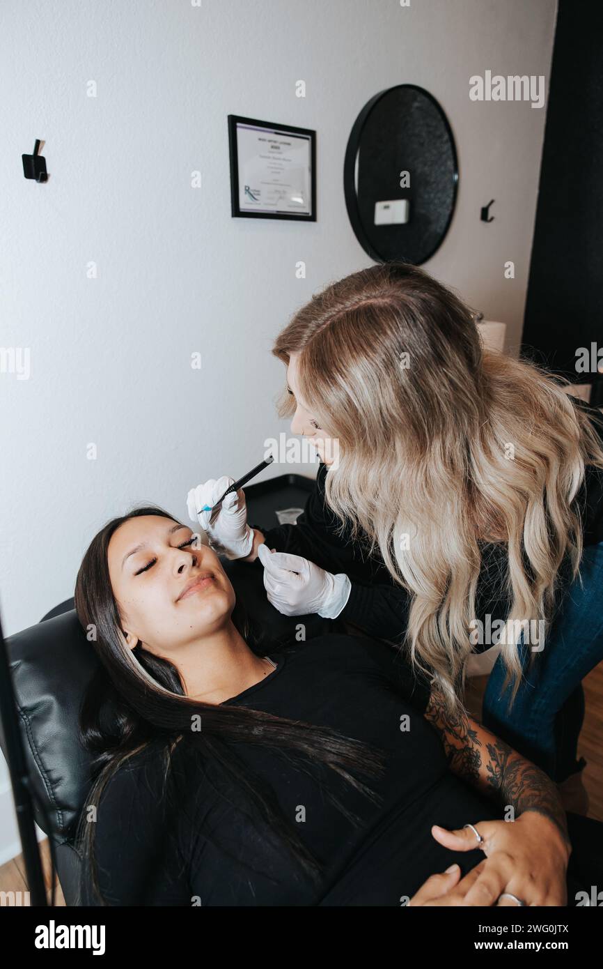 Blonde artist, permanent makeup for client in chair Stock Photo - Alamy