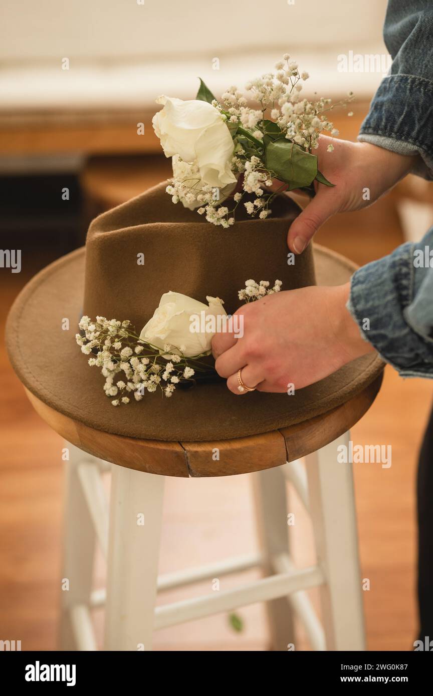Woman decorating the top of a hat with roses and baby's breath flowers ...