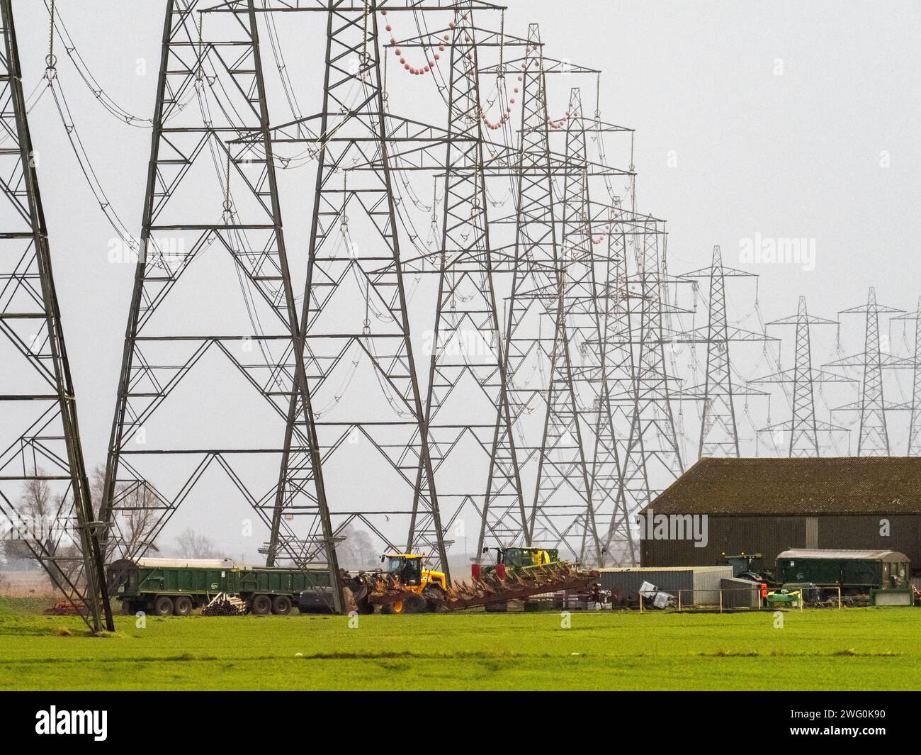 Electricity pylons crossing farmland on the Fens near Welney, Norfolk ...