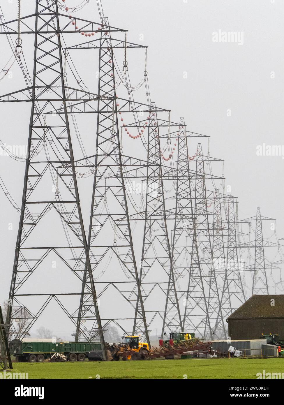 Electricity pylons crossing farmland on the Fens near Welney, Norfolk ...