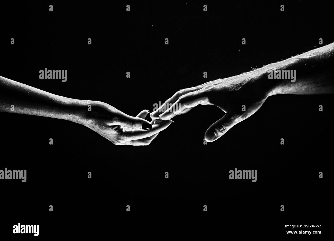 Two hands stretch each other, black background. Couple in love holding hads, close up. Helping ...