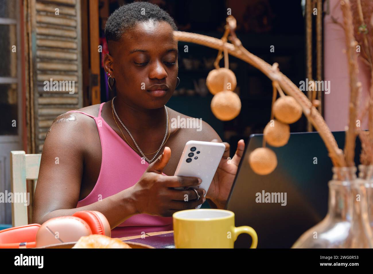 young afro woman of Haitian ethnicity, at home using phone touching ...