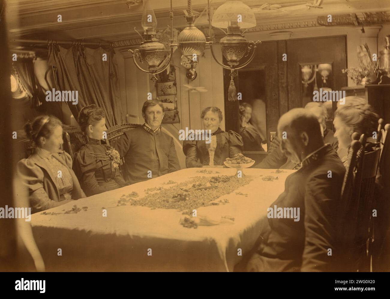 Captains, their wives, and two female tourists sitting around a table ...