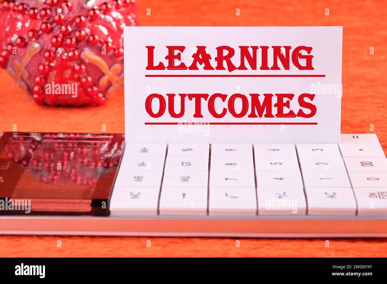 Learning Outcome write on a white business card on a calculator on an ...