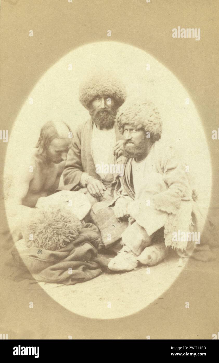 Full-length portrait of three men, seated on ground, facing front ...