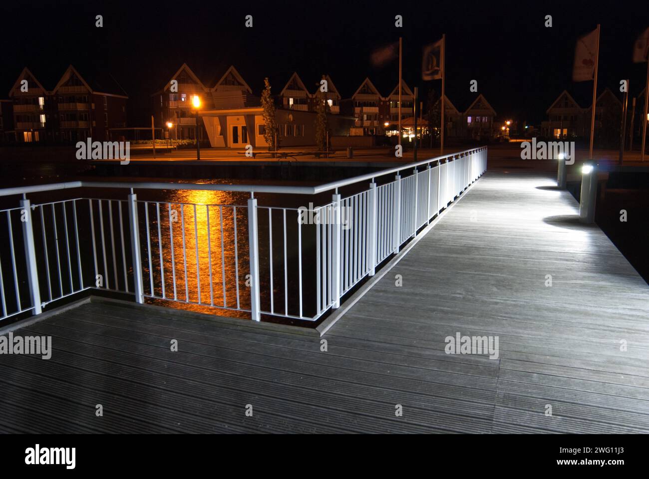 Pier with illuminated lamps, railings and light reflections in the ...