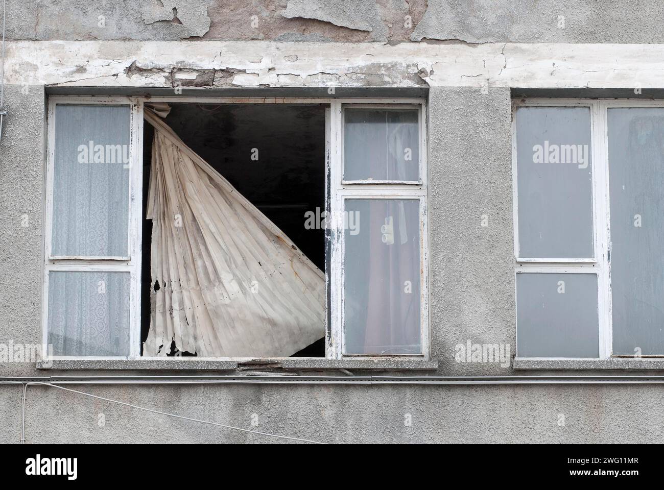 A damaged window with a torn blind in a decaying building, facade ...