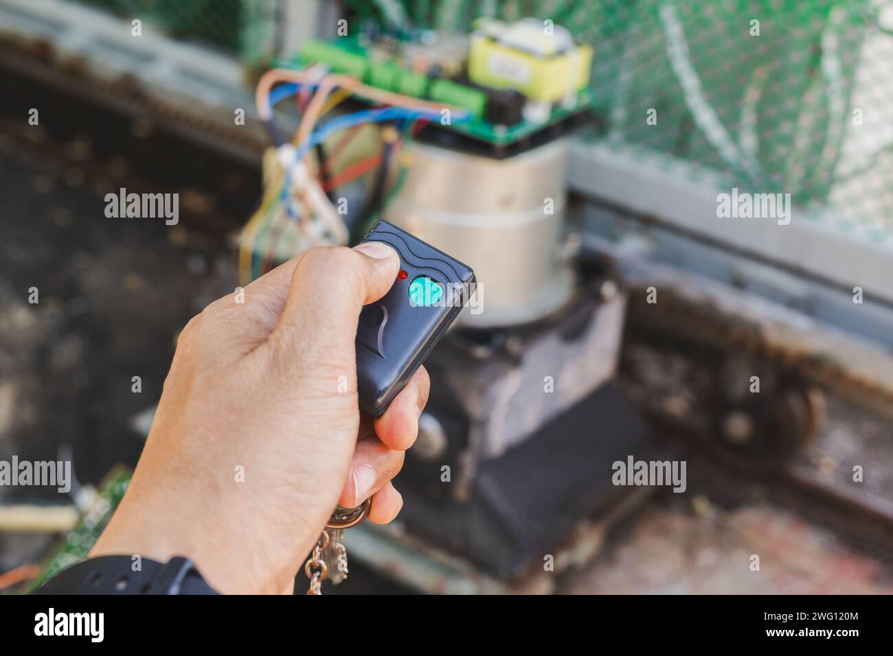 Man hand pressing remote control to open gate door Stock Photo - Alamy