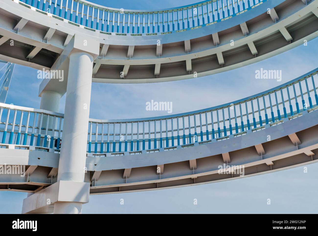 Two parts of a circular ramp of pedestrian bridge with blue cloudy sky ...