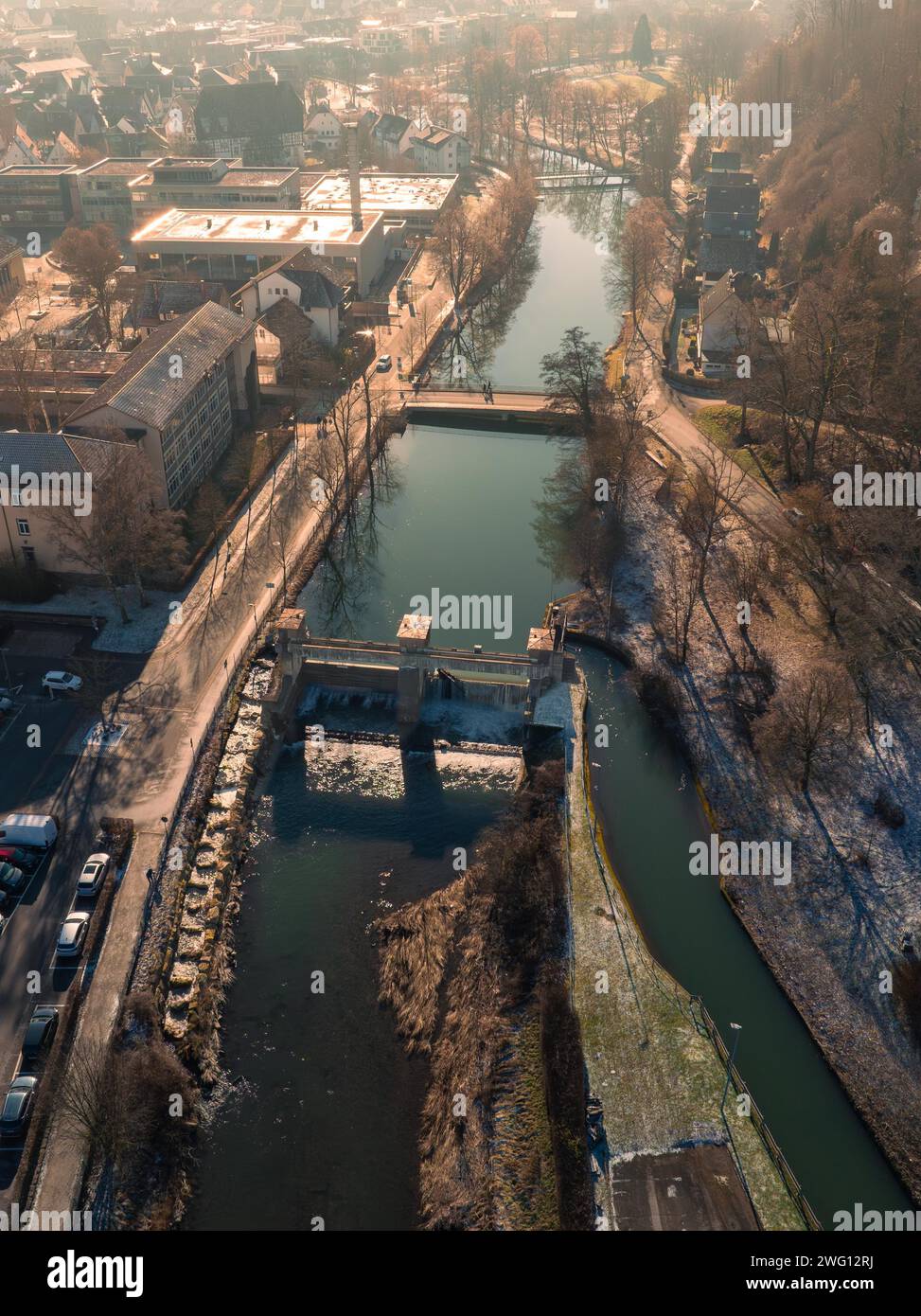 Sunny river bank with bridge and neighbouring buildings, aerial view ...