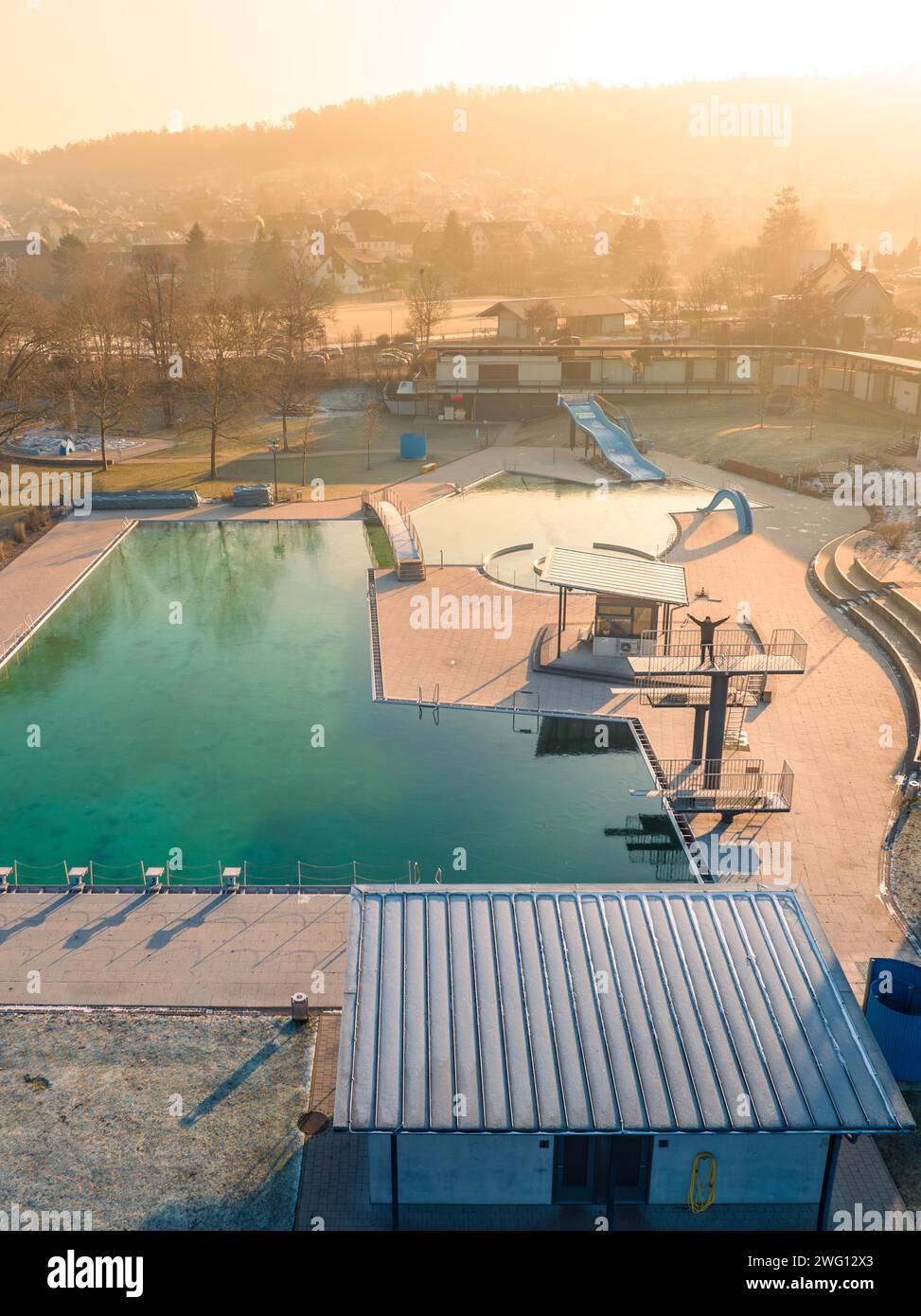 Winter sunrise over a quiet swimming pool with slide and frost-covered ...