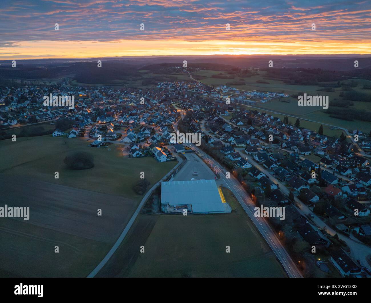 Aerial view of a village at sunset with warm colours and dark clouds ...