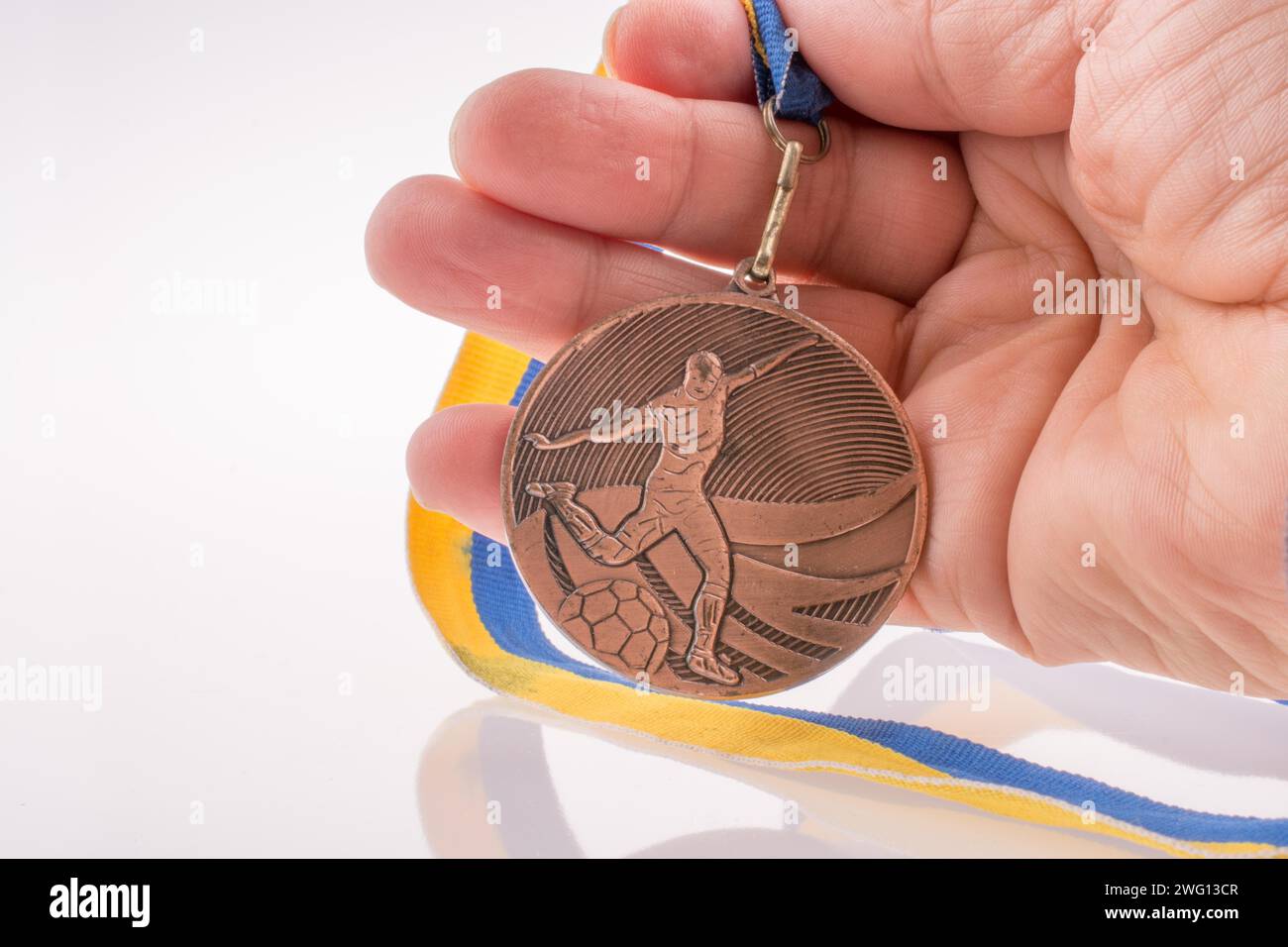 Hand holding a medal with blue and yellow ribbon Stock Photo - Alamy