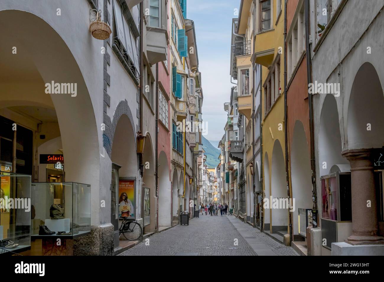 View through a lively pedestrian zone with arcades and shops, historic ...