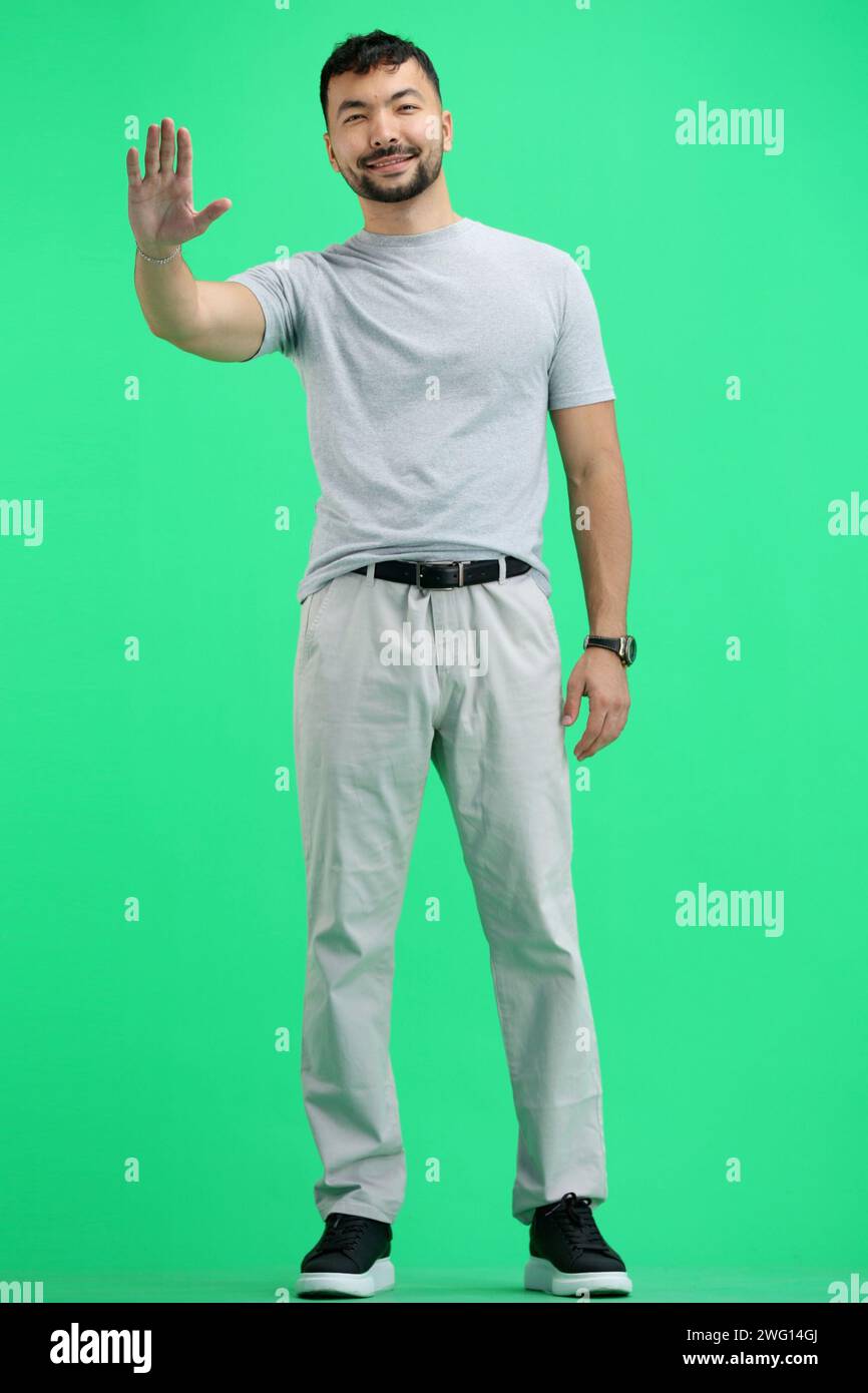 A man, full-length, on a green background, waving his hand Stock Photo ...