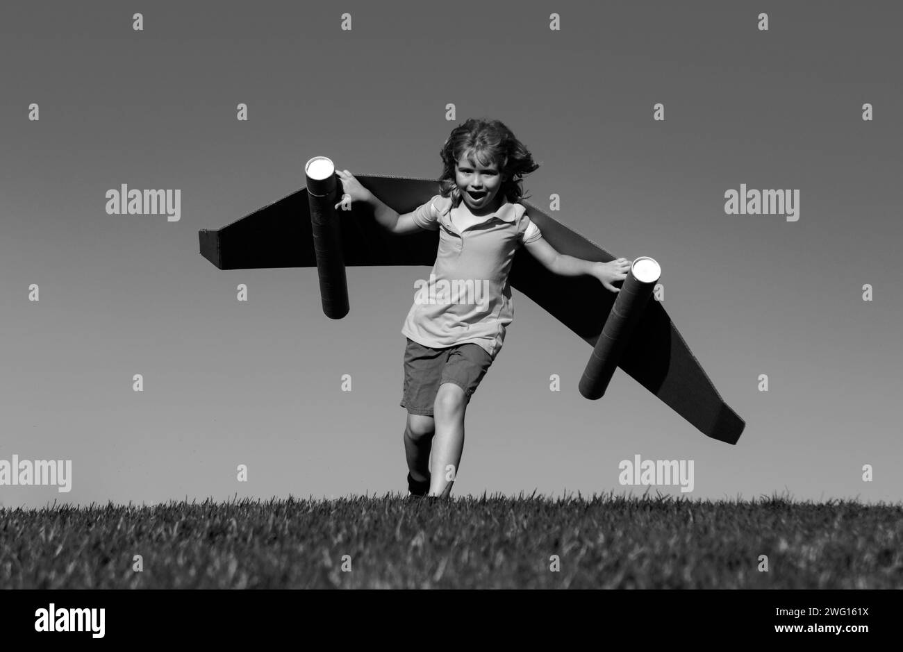 Excited child running with paper wings against blue sky. Kid with toy ...