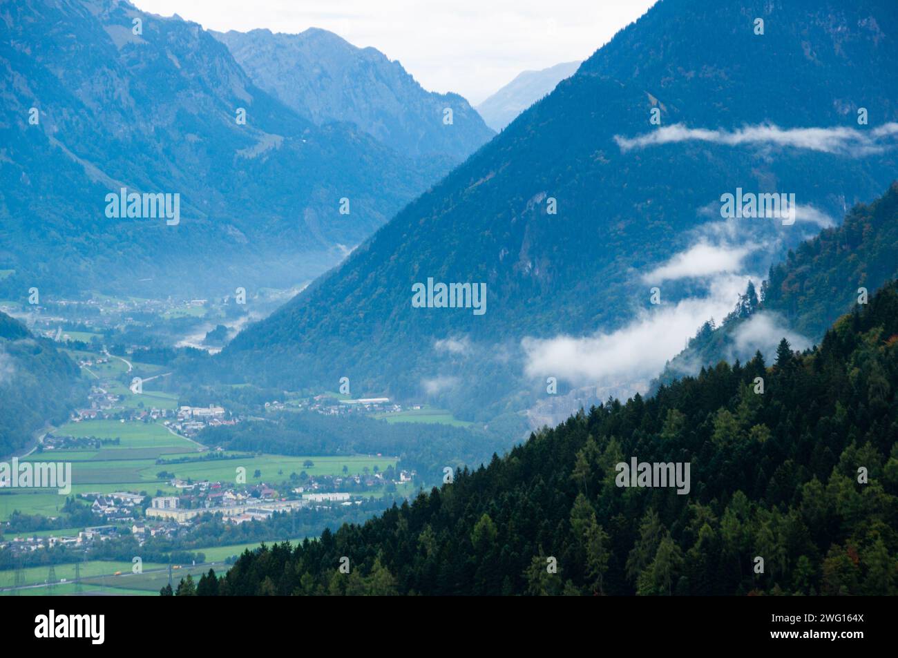 An aerial view of forested mountain slopes with clouds in the Alps ...