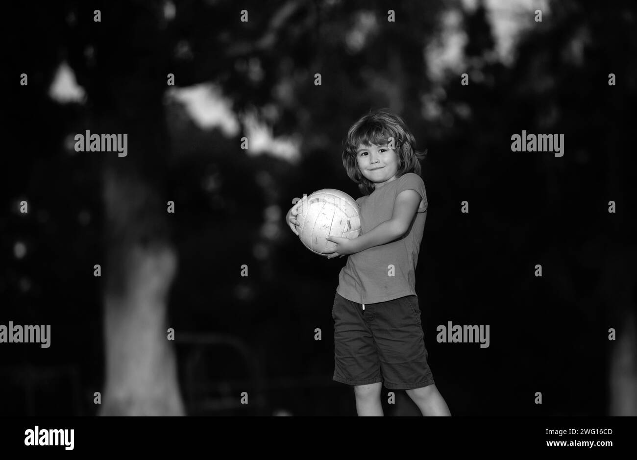 Excited child boy kicking ball in the grass outdoors. Soccer kids ...