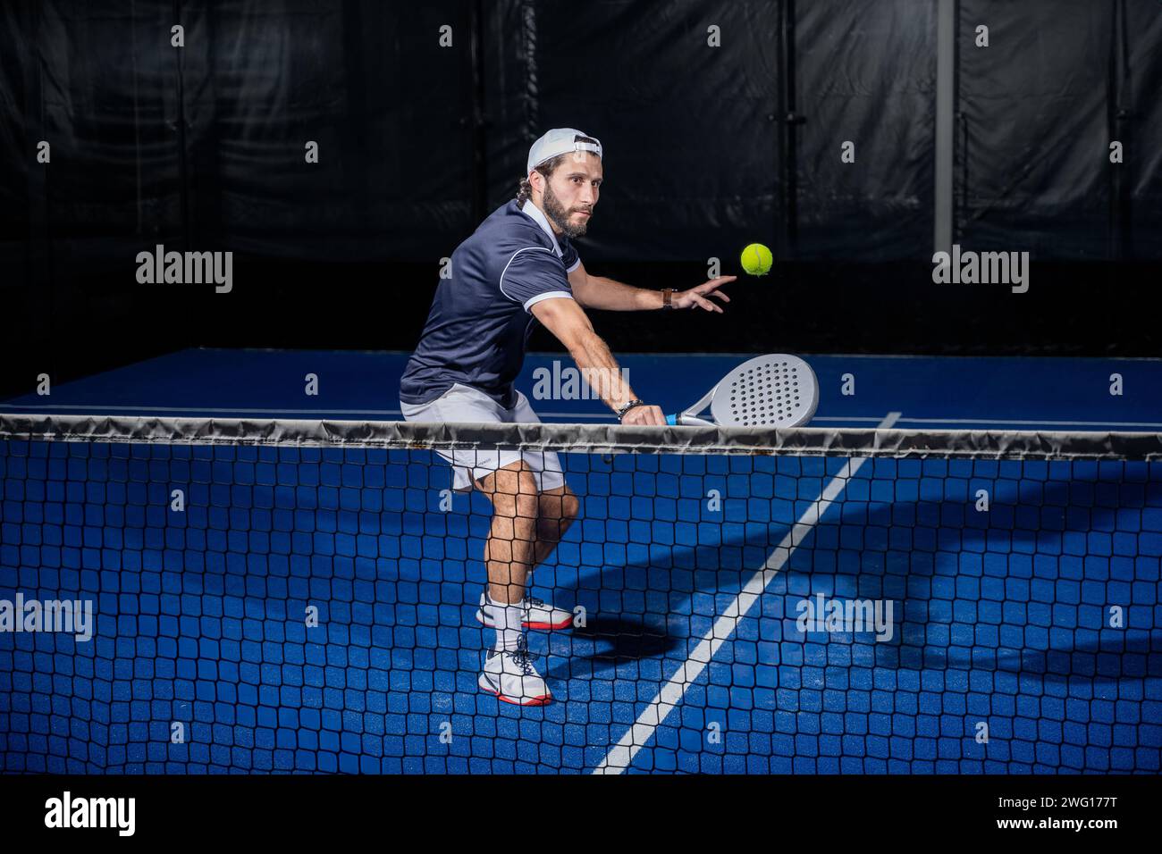 Man playing padel in a blue indoor padel court padel - Young sporty boy ...