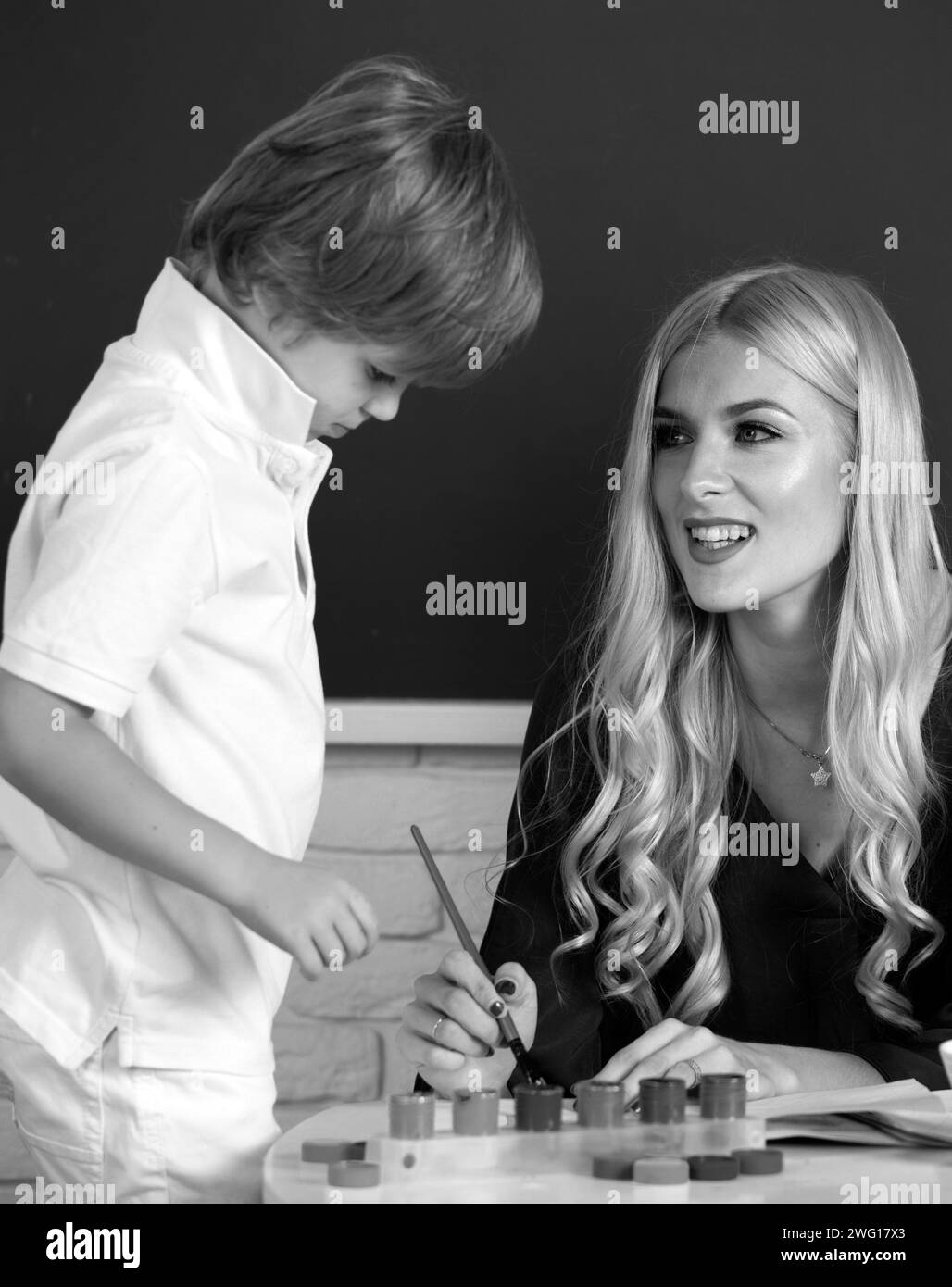 Mother and two son together draw, paint. Mom helps the child boy ...