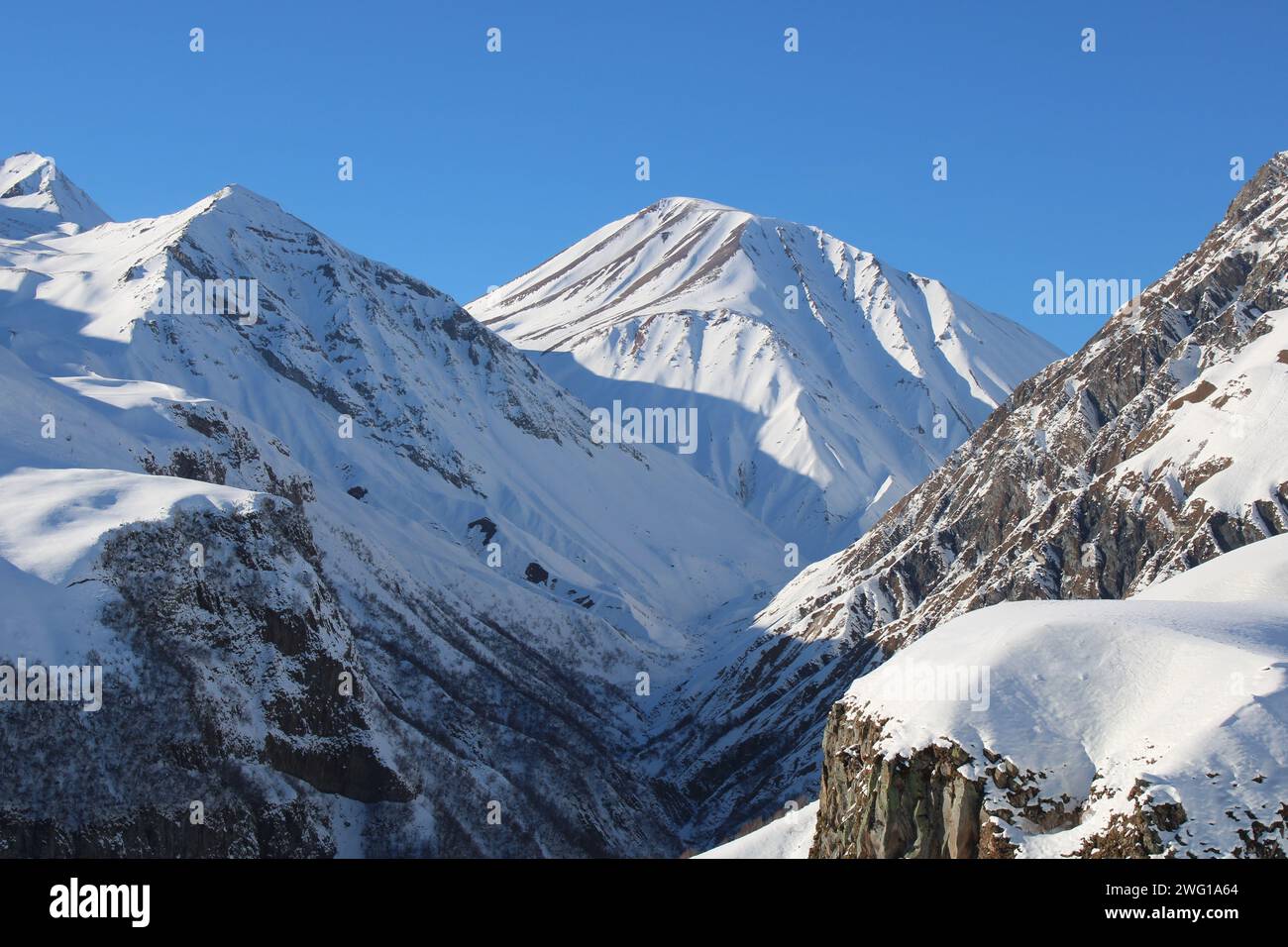 Sunny day in caucasus mountains. Snow peaks and rocks, deep gorge ...