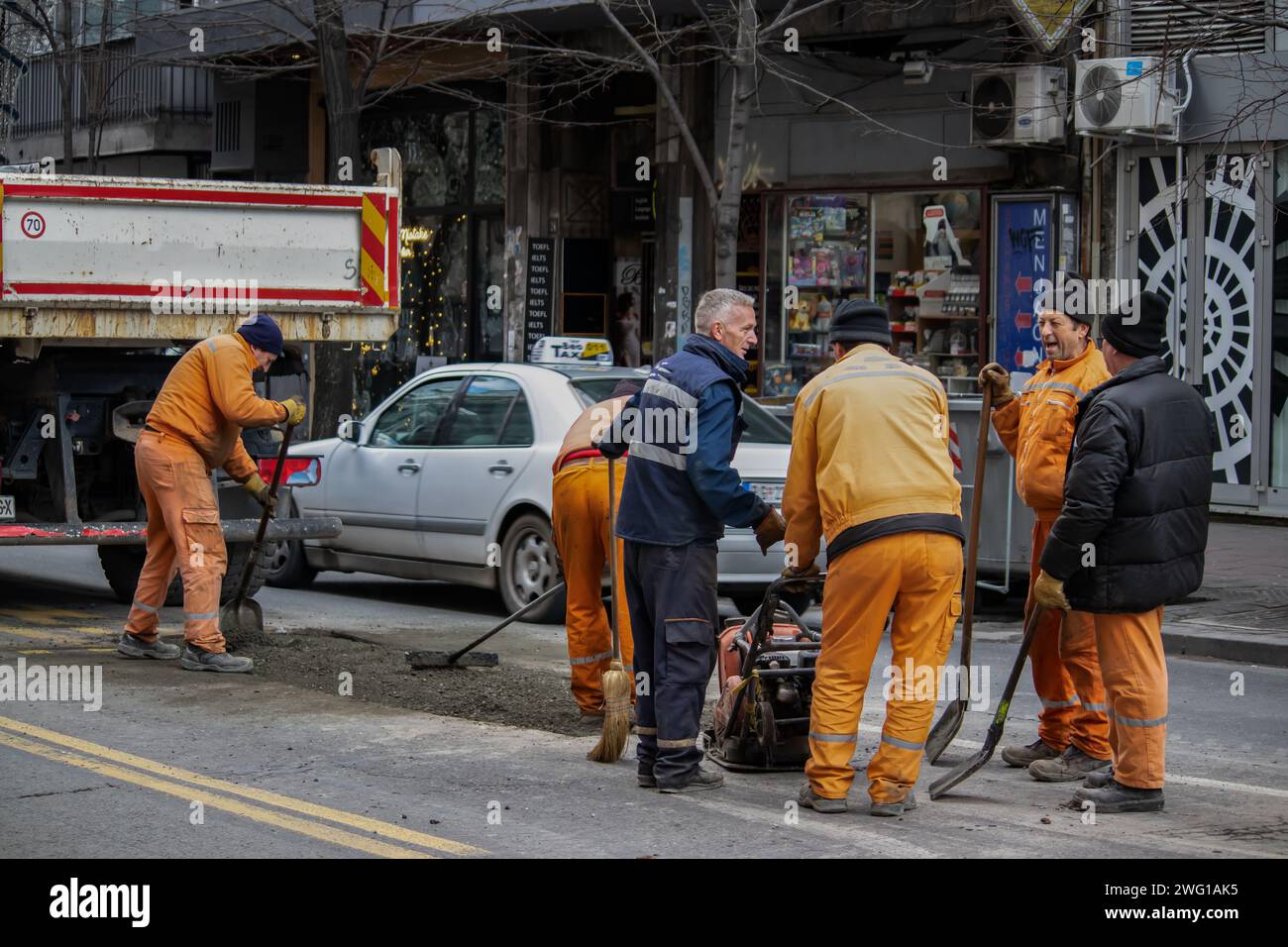 Workers in orange uniforms and protection equipment fixing and patching ...