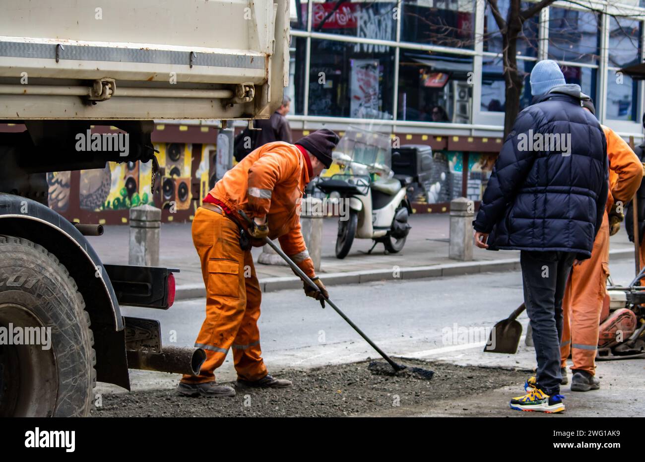 Workers in orange uniforms and protection equipment fixing and patching ...