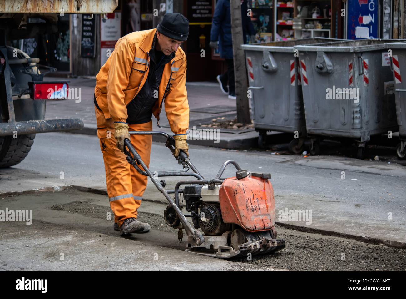 Workers in orange uniforms and protection equipment fixing and patching ...