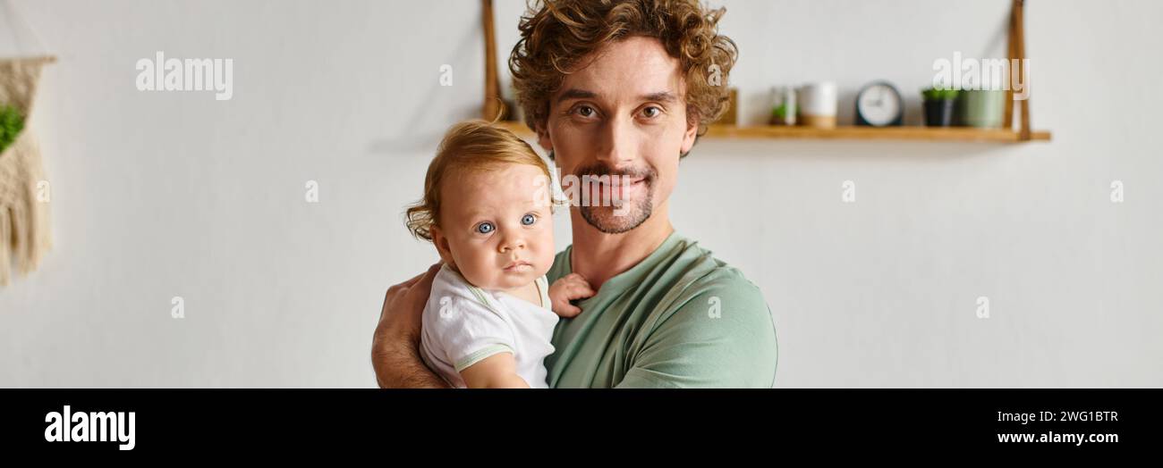 curly haired father with beard holding his infant son with blue eyes in ...