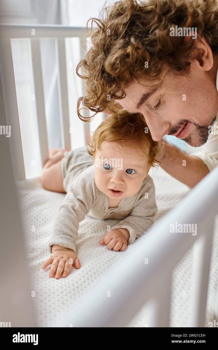 happy father with beard and curly hair embracing blue eyed baby boy in ...