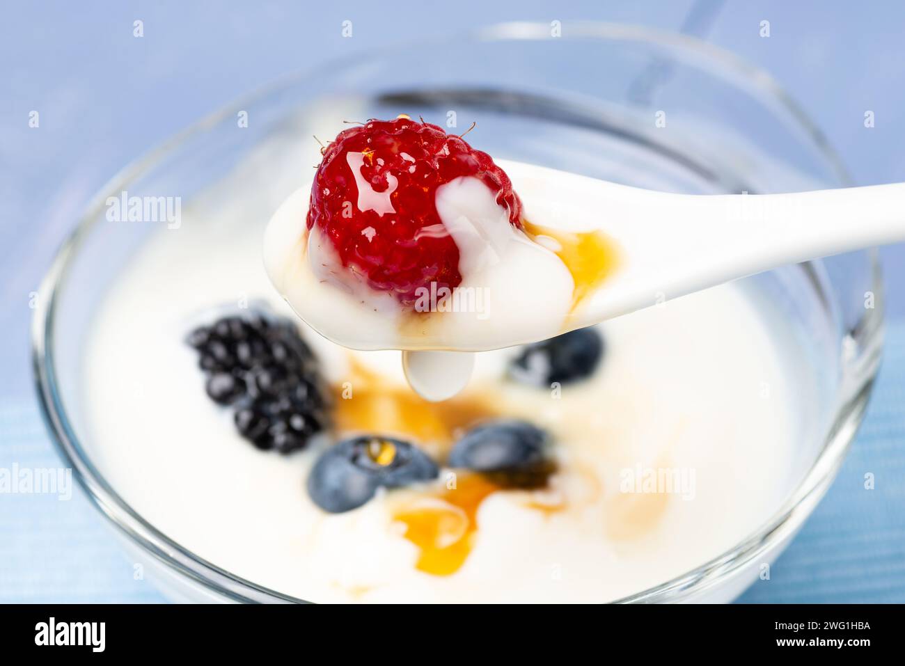 in the foreground a spoonful of low-fat yogurt with red raspberry and ...