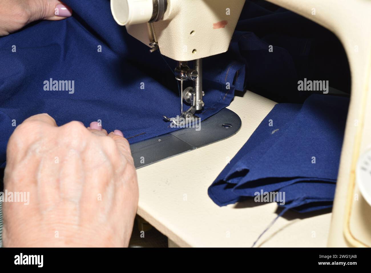 The hands of a seamstress straightens the fabric, which lies on the ...