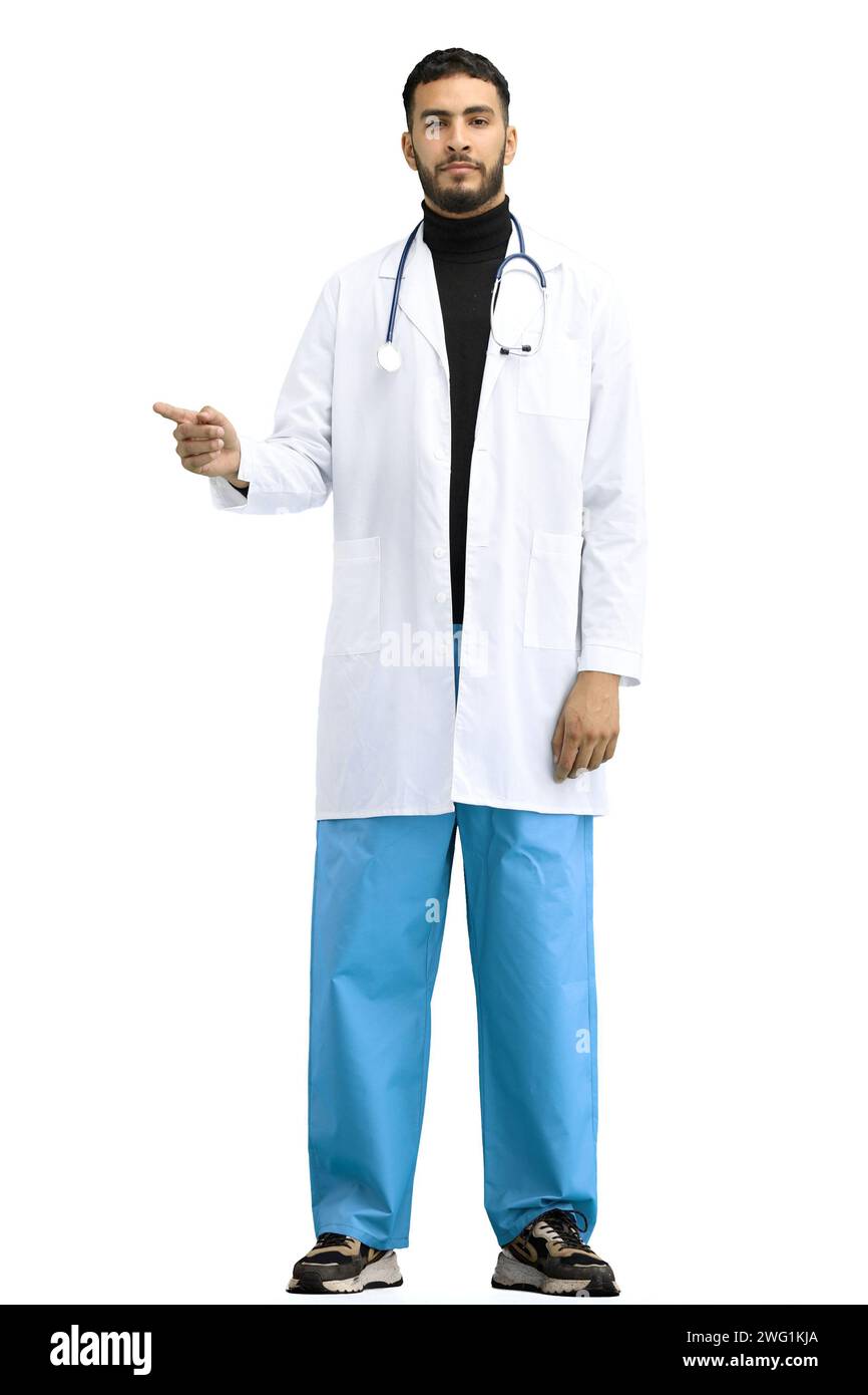 The doctor, in full height, on a white background, points to the side ...