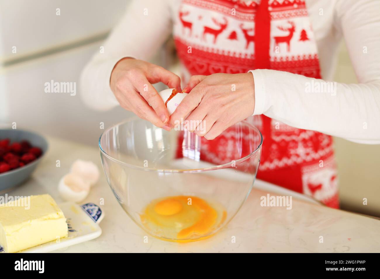 female hands breaking an egg into a glass bowl, female hands breaking an egg into a glass bowl ...