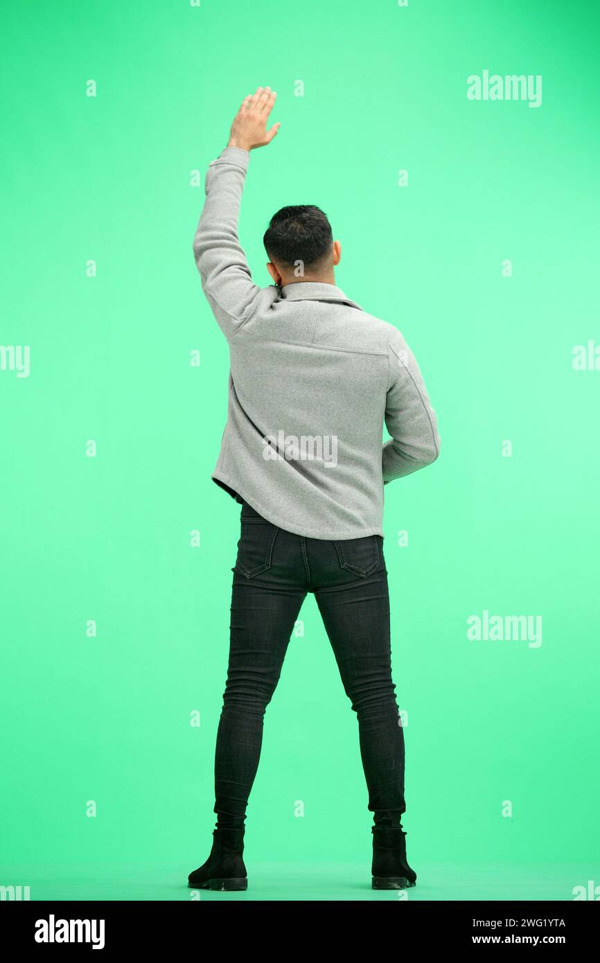 A man, full-length, on a green background, waving his hand Stock Photo ...