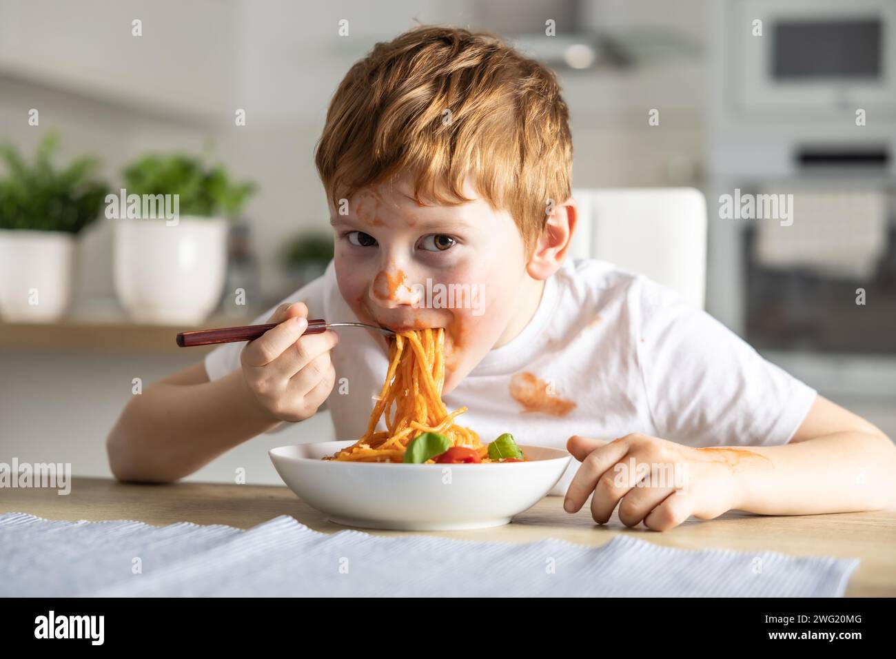 A cute little boy is eating spaghetti bolognese for lunch in the ...