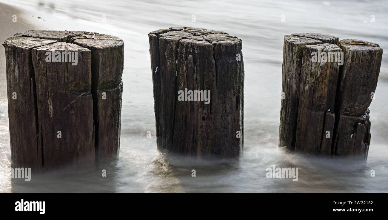 Close-up of three wooden groynes in the Baltic Sea with long exposure ...