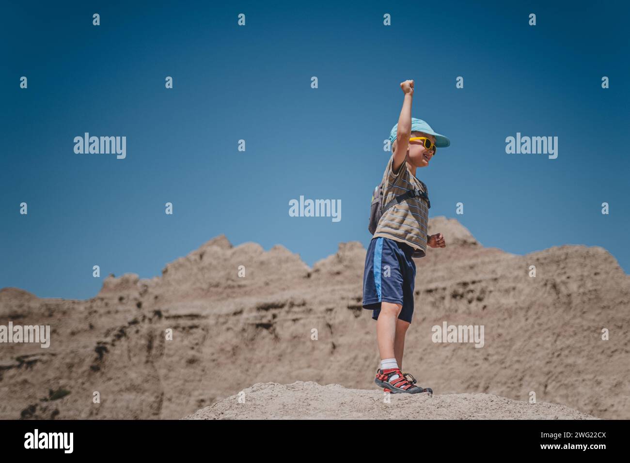 Young boy raising his hand on top of a rock formation of Badlands ...