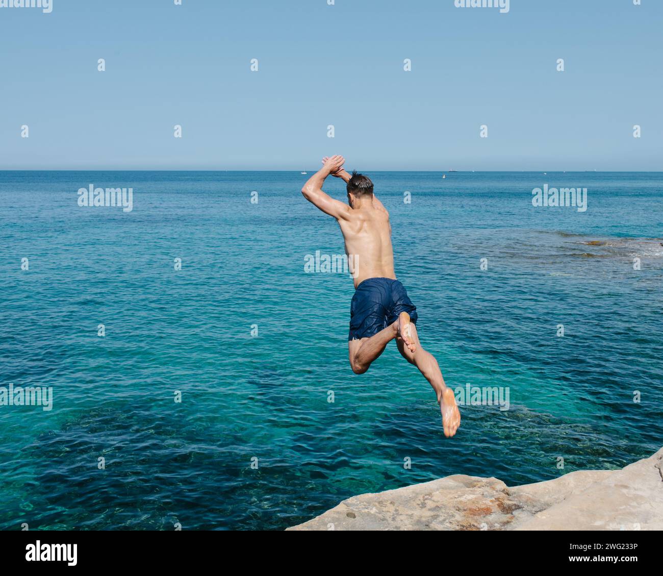 A man jumps into the sea from the rocks on a private beach in Valetta ...