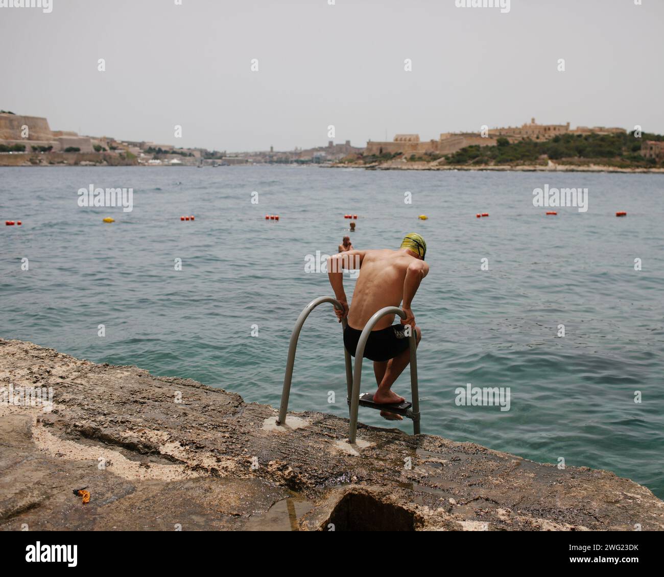A swimmer prepares to get into the sea at Tigne Point beach, Malta ...