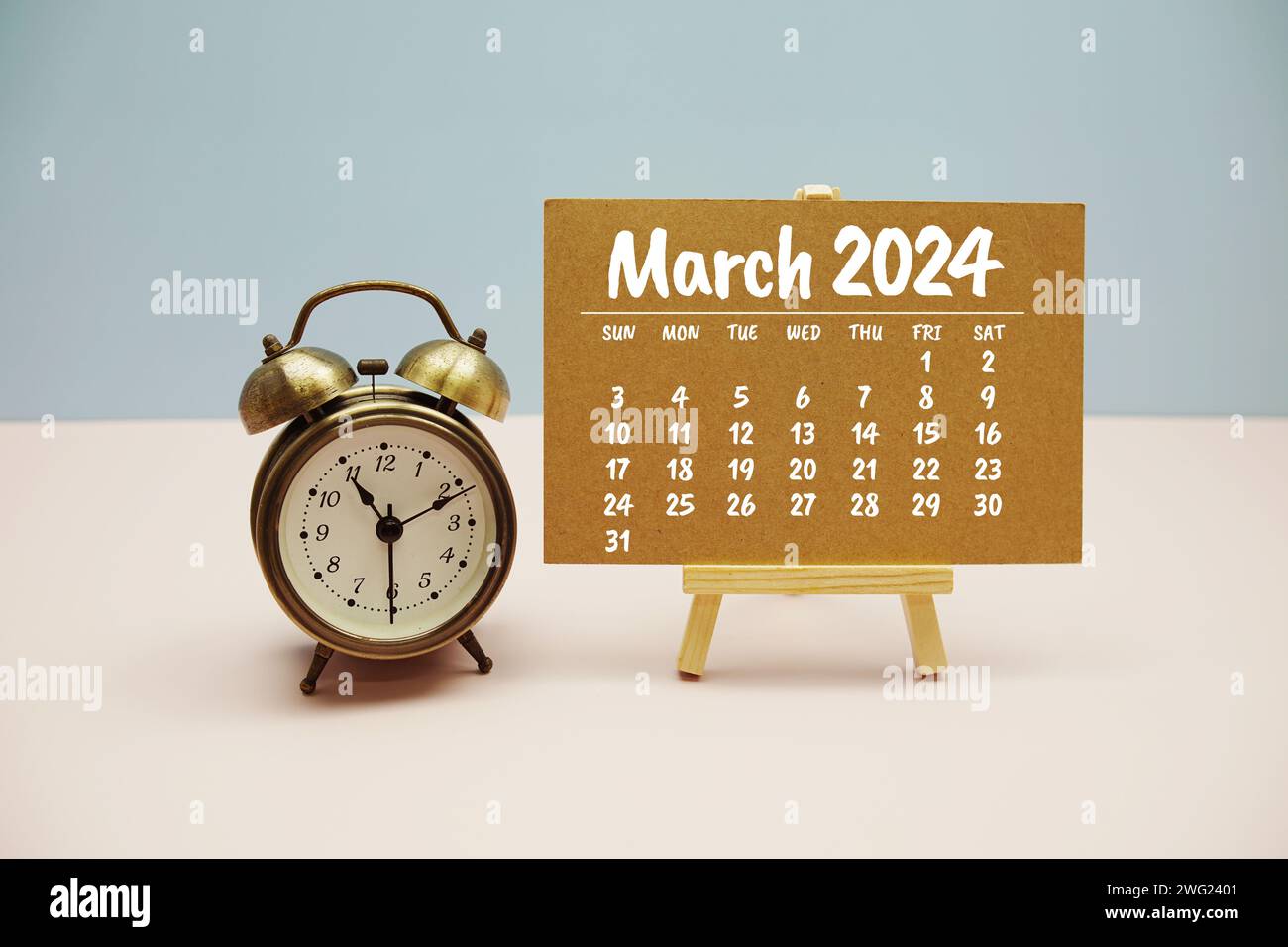 March 2024 monthly calendar on easel stand with alarm clock on pastel ...