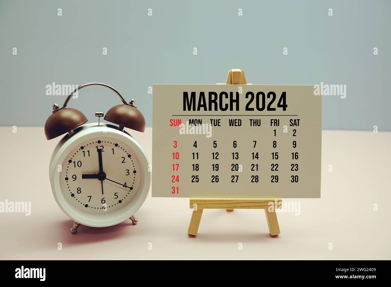 March 2024 monthly calendar on easel stand with alarm clock on pastel ...