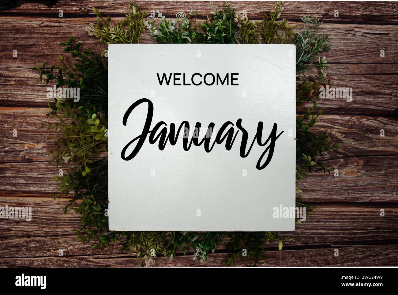 Welcome January text message with green leaf decoration on wooden ...