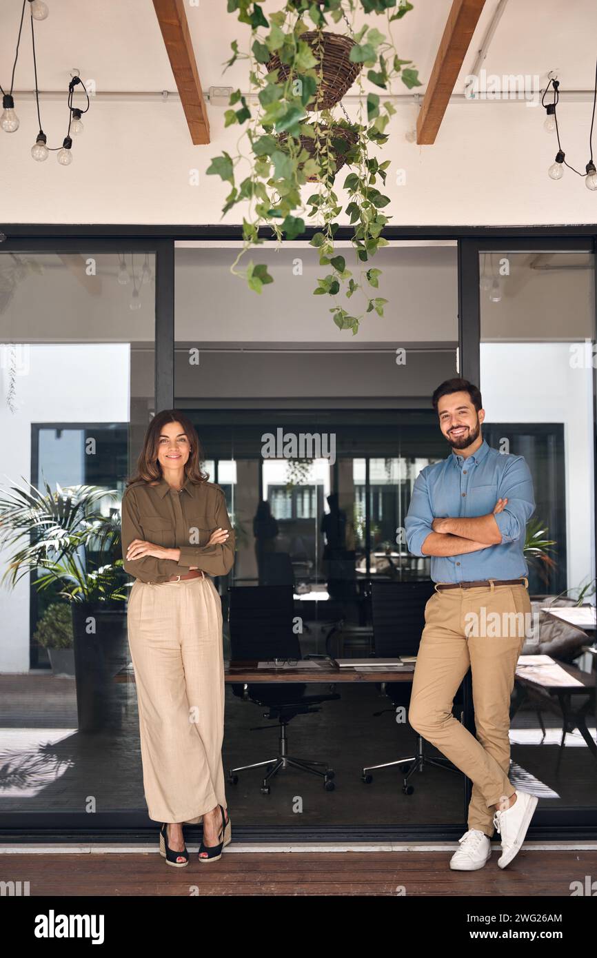 Two business partners standing in modern cozy office, vertical portrait ...