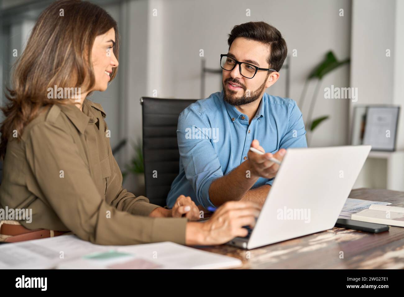 Busy professional workers working in office with laptop and talking ...