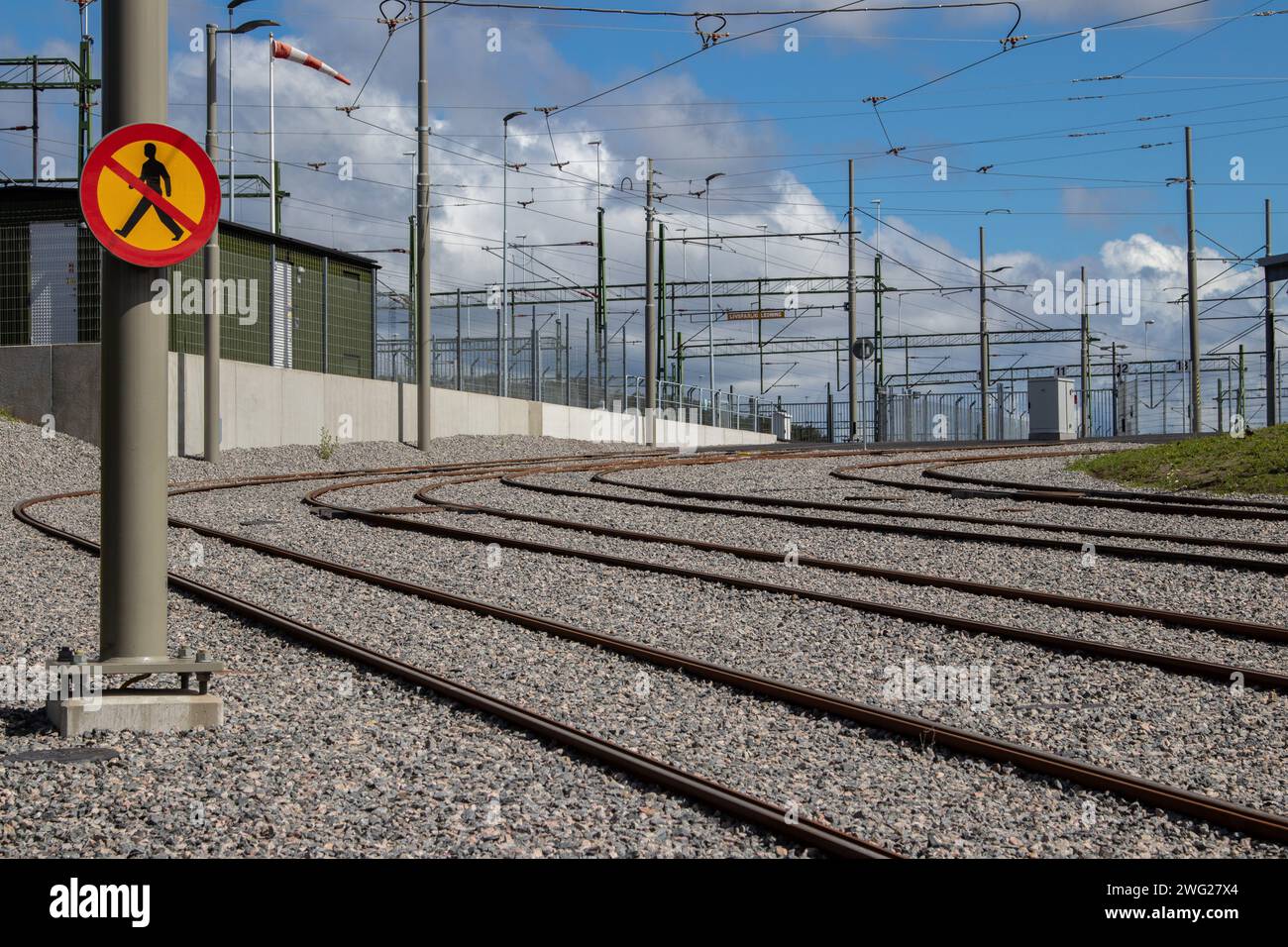 Train tracks in a curb. No walking sign and electrical cables. No ...