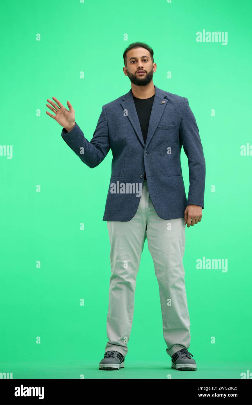 A man, full-length, on a green background, waving his hand Stock Photo ...