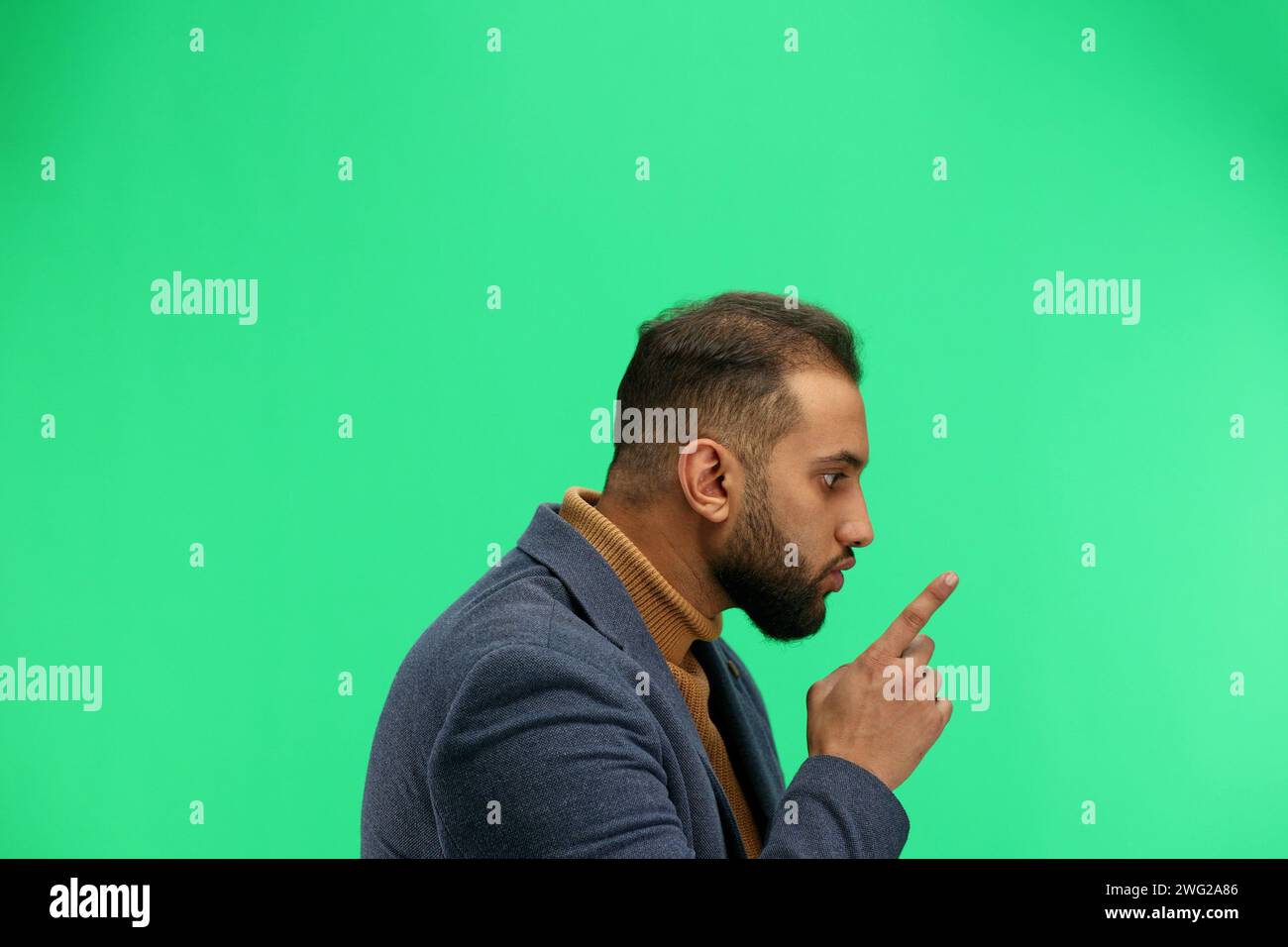 A man, close-up, on a green background, shows a sign of silence Stock ...