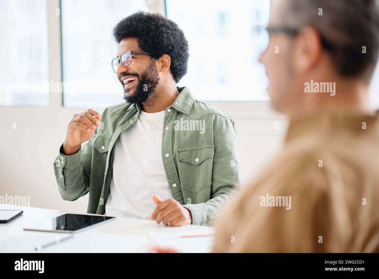 In a well-lit office man with a contagious laugh shares a joke with his ...